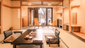 Um quarto japonês tradicional com tatames, uma mesa baixa com almofadas e portas deslizantes que dão para uma varanda.