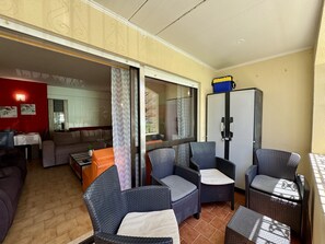 Quarto com mobiliário em vime, um sofá, uma mesa e um armário.