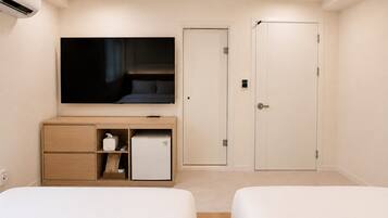 Quarto de hotel com duas camas, televisão, minibar e uma porta.