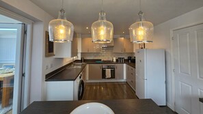 Uma cozinha moderna com ilha central, eletrodomésticos de aço inoxidável e iluminação pendente.