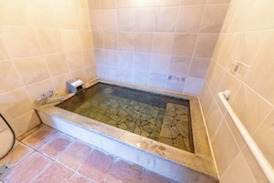 Uma banheira com interior revestido em azulejos e ralo.
