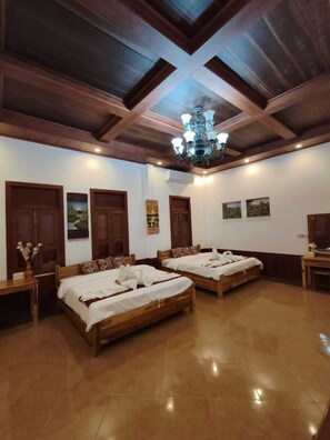 Quarto com camas de madeira, um candelabro e obras de arte nas paredes.