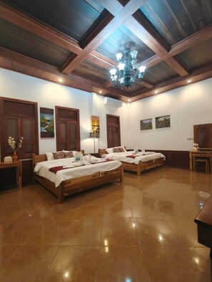 Quarto com três camas de madeira, um candelabro e obras de arte nas paredes.