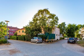 Rua residencial com carros estacionados, casas e árvores.