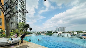 Piscina com espreguiçadeiras e vista para a paisagem urbana.