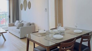 Uma área de jantar moderna com mesa de vidro, cadeiras de madeira e um lustre.