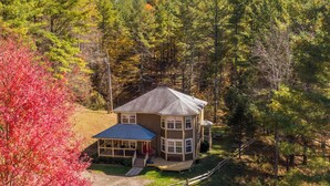 Uma casa de dois andares com varanda, cercada por uma floresta.