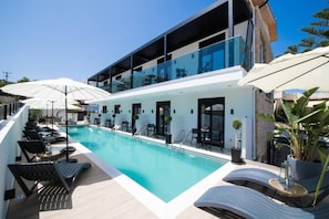 Um hotel moderno com piscina, área de estar ao ar livre e um nível superior envidraçado.