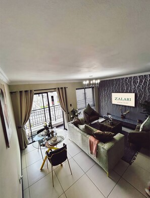 Uma sala de estar moderna com sofá, mesa de jantar e lustre.