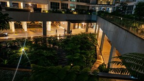 Uma área externa em vários níveis com estruturas de concreto, vegetação e um espelho d'água.