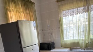 Uma cozinha compacta com geladeira, micro-ondas e armários de madeira.