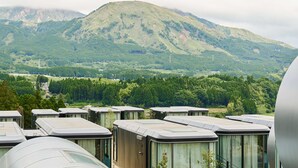 Fileira de casas móveis modernas e retangulares, com grandes janelas, diante de uma floresta verde e uma montanha.