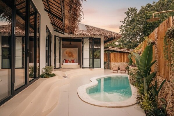 Uma casa moderna com piscina, grandes portas de vidro e telhado de palha.