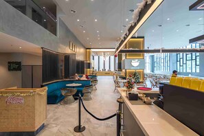 Um lobby de hotel moderno com uma receção, área de estar e vista para a cidade.