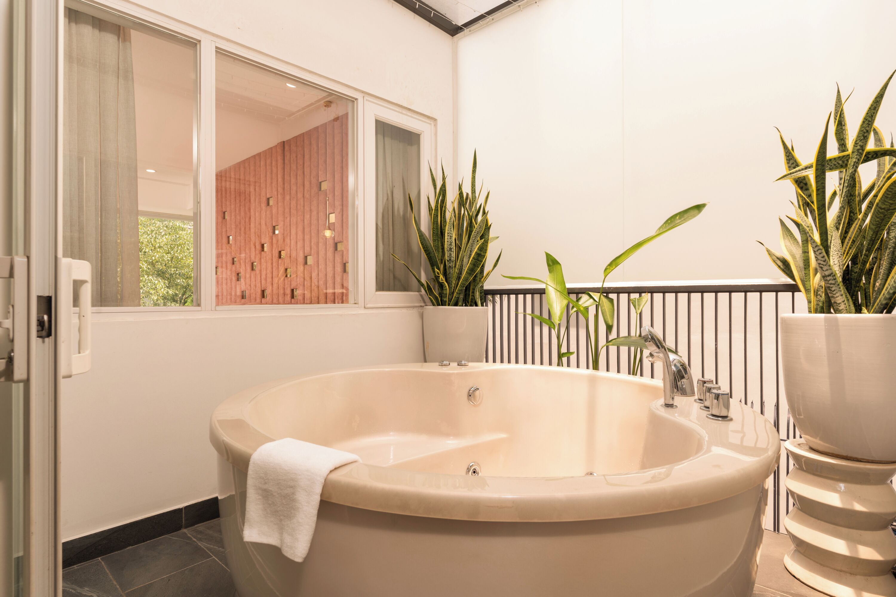 Uma casa de banho moderna com uma banheira independente, uma janela e plantas em vasos.