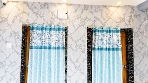 Duas portas com cortinas estampadas, uma parede de mármore e uma câmera de segurança.