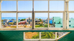 Janela com vista para uma vila costeira, incluindo edifícios e o mar.
