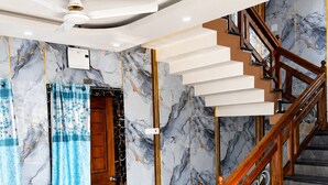 Um interior moderno com parede de mármore, escada de madeira e ventilador de teto.