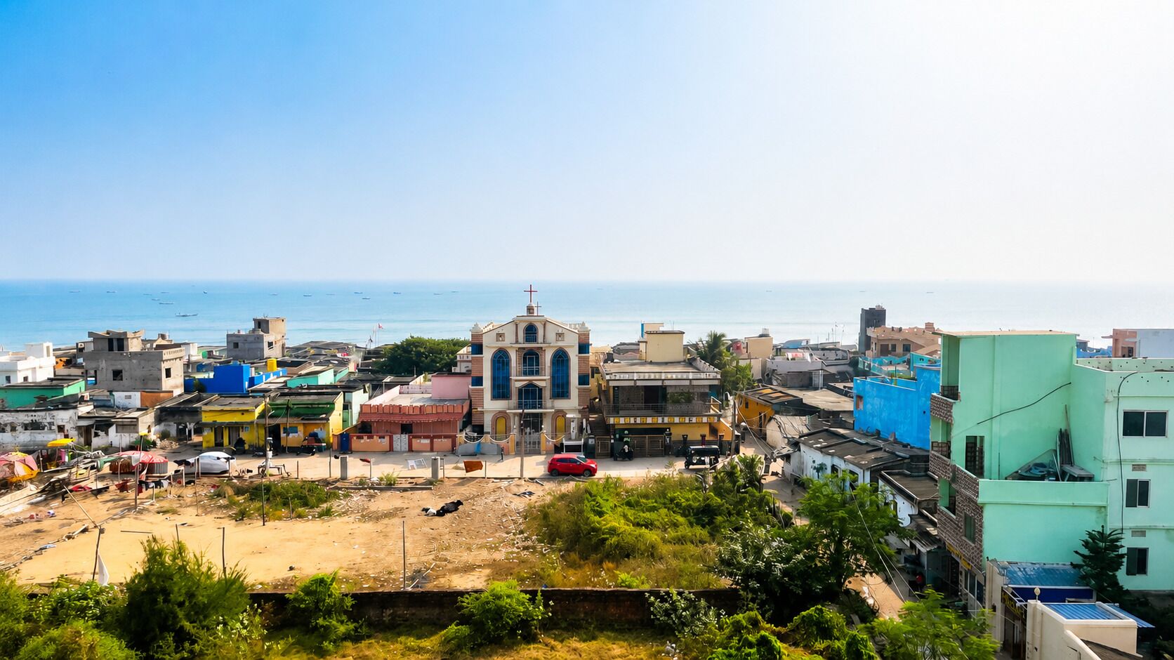 Uma cidade costeira com edifícios, praia e o mar ao fundo.