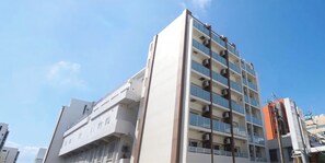 Um edifício com vários andares, varandas, aparelhos de ar condicionado e um céu claro.
