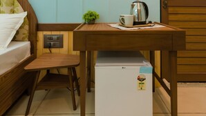A compact room with a bed, a small table, a refrigerator, and a door.