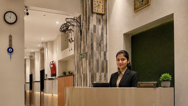 A hotel reception area with a curved reception desk, a clock, and a ceiling fan.