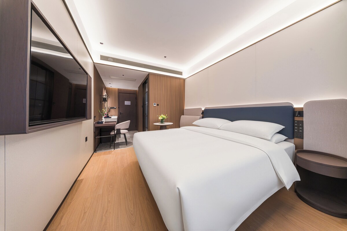 Quarto de hotel moderno com uma cama grande, uma escrivaninha e uma cadeira.