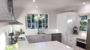 Cozinha moderna com armários brancos, uma ilha grande e uma janela com vista para o verde.
