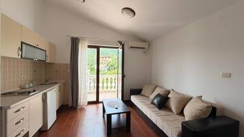 Um espaço de estar compacto com cozinha compacta, sofá, mesa de centro e varanda com vista.