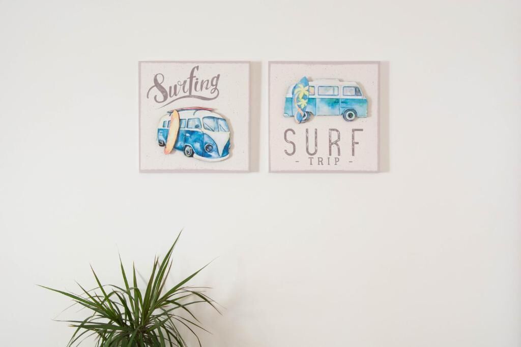 Duas obras de arte na parede retratam carros antigos e as palavras 'Surfing' e 'Surf Trip'.