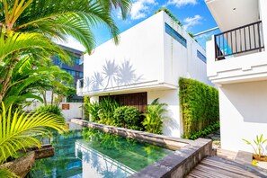 Um edifício moderno com piscina, rodeado por vegetação exuberante e palmeiras.
