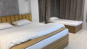 Quarto de hotel moderno com uma cama grande, uma cama menor, um ventilador de teto e uma parede estampada.
