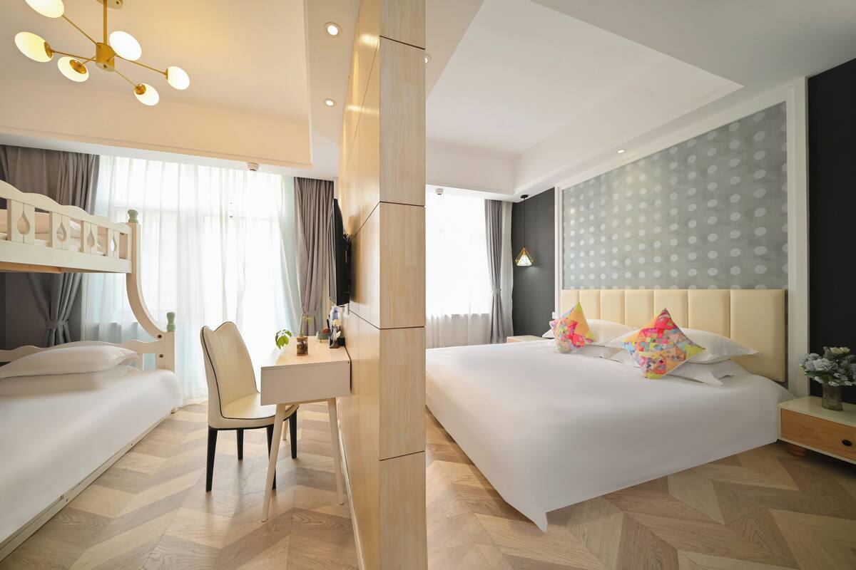 Quarto de hotel moderno com cama, escrivaninha, cadeira e um espelho grande.