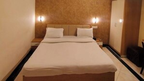 Quarto de hotel com cama, mesas de cabeceira, ventoinha no teto e espelho.