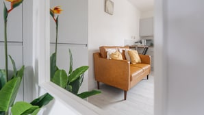 Uma sala de estar moderna com um sofá de couro, um espelho grande e um vaso de planta.