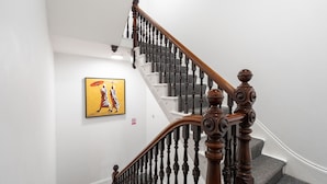Uma escadaria com balaústres de madeira e corrimão, um quadro na parede e um aviso de proibido fumar.