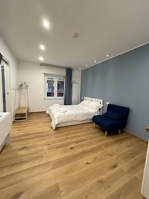 Quarto com cama, uma cadeira, uma janela e uma escada.
