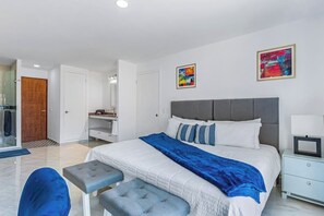 Um quarto moderno com cama, mesas de cabeceira, um banco e obras de arte nas paredes.