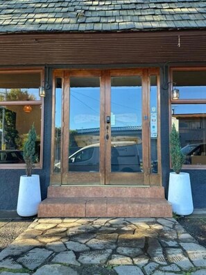 Um edifício com fachada de madeira, grandes portas de vidro e plantas em vasos.