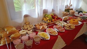 Mesa de buffet com diversos alimentos e vista para a janela.