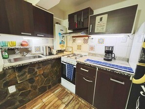 Uma cozinha compacta com fogão a gás, pia e cafeteira.