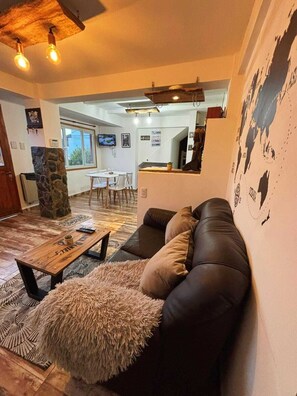 Uma sala de estar com um sofá de couro, uma mesa de centro de madeira e um pilar de pedra.