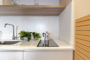 Uma cozinha moderna com uma pia de aço inoxidável, uma cafeteira e um vaso com planta.