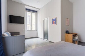 Quarto de hotel moderno com cama, televisão, escrivaninha e cadeira.