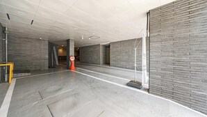 Um espaço interno amplo com pé direito alto, paredes de tijolo cinza e piso de concreto polido.