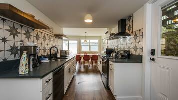 Uma cozinha com ilha central, armários brancos e backsplash estampado.