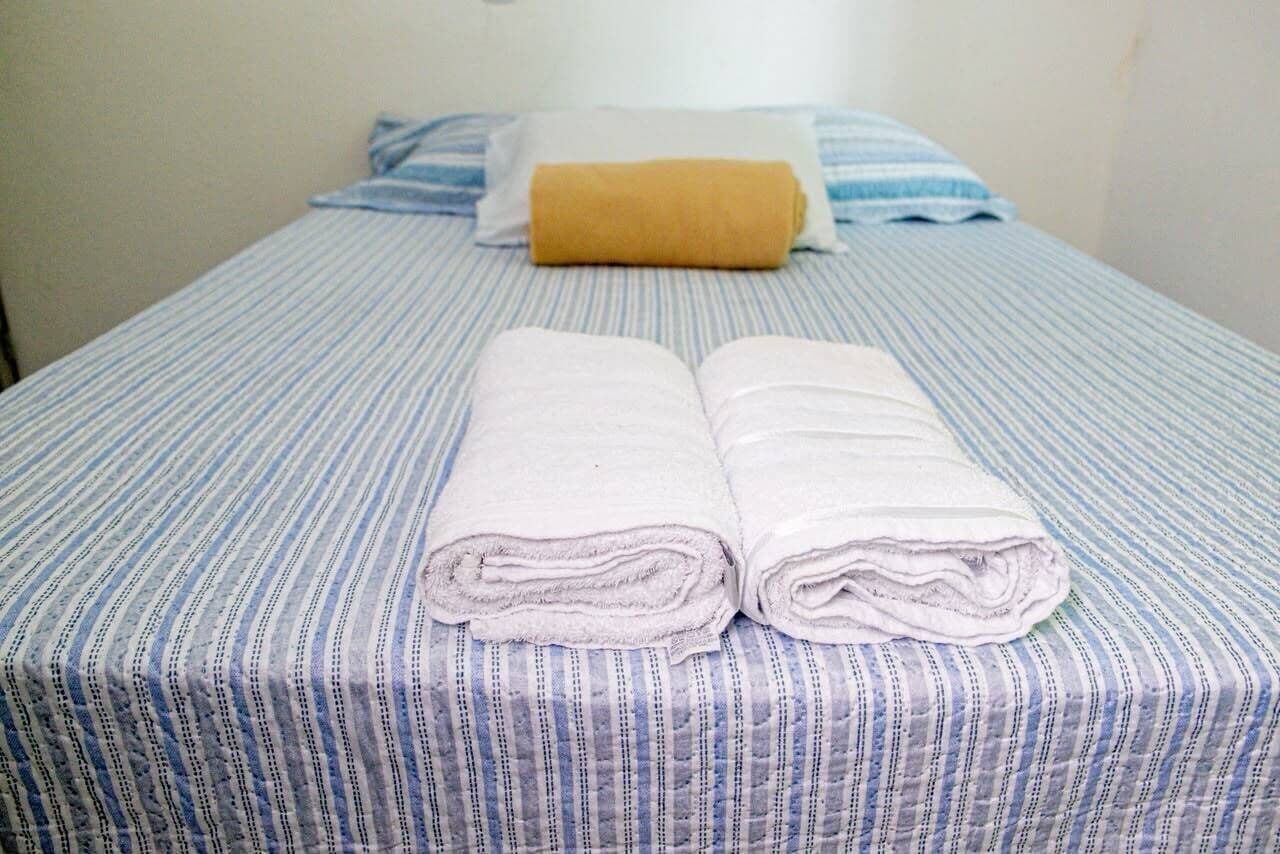 Uma cama com colcha listrada e duas toalhas enroladas.