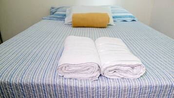 Uma cama com colcha listrada e duas toalhas enroladas.