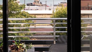 Uma varanda com vista para uma ponte, uma rua e um corpo de água.