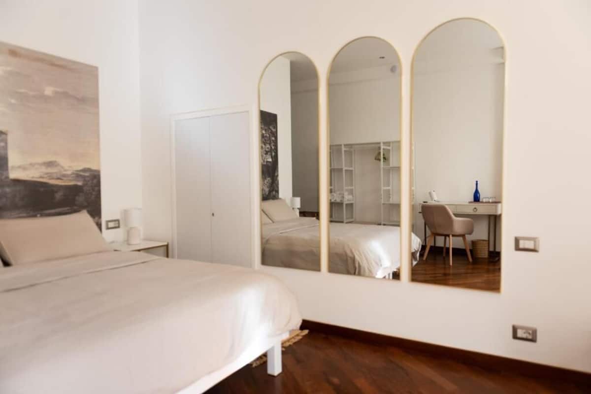 Um quarto com cama, escrivaninha, cadeira e guarda-roupa.